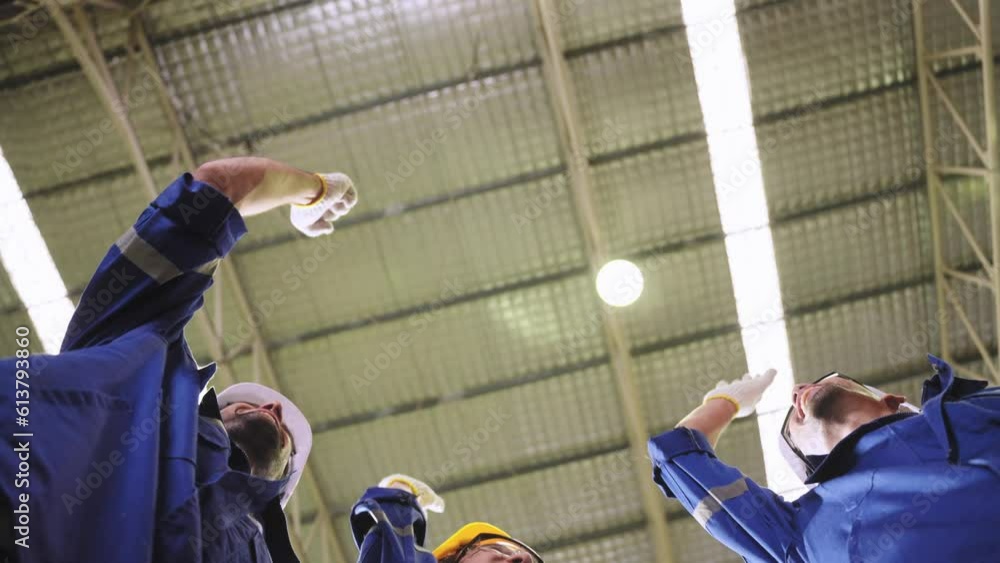 Team of factory workers celebrate a great success by joining hands ...