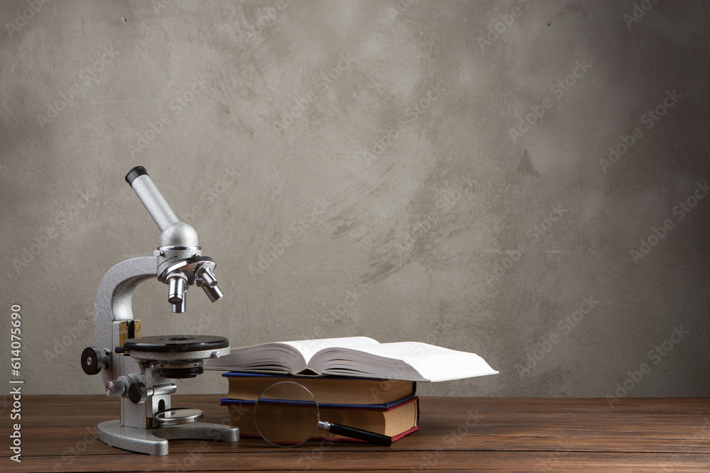 Back to school - books and microscope on the wooden desk in the ...