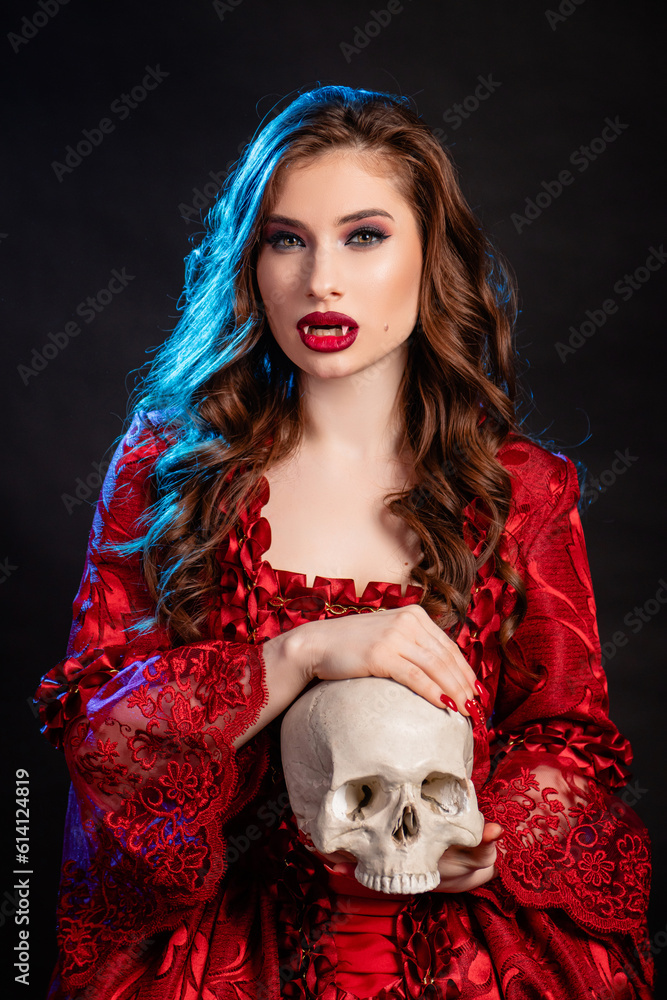 Portrait of a young, attractive vampire woman in a red dress in the ...