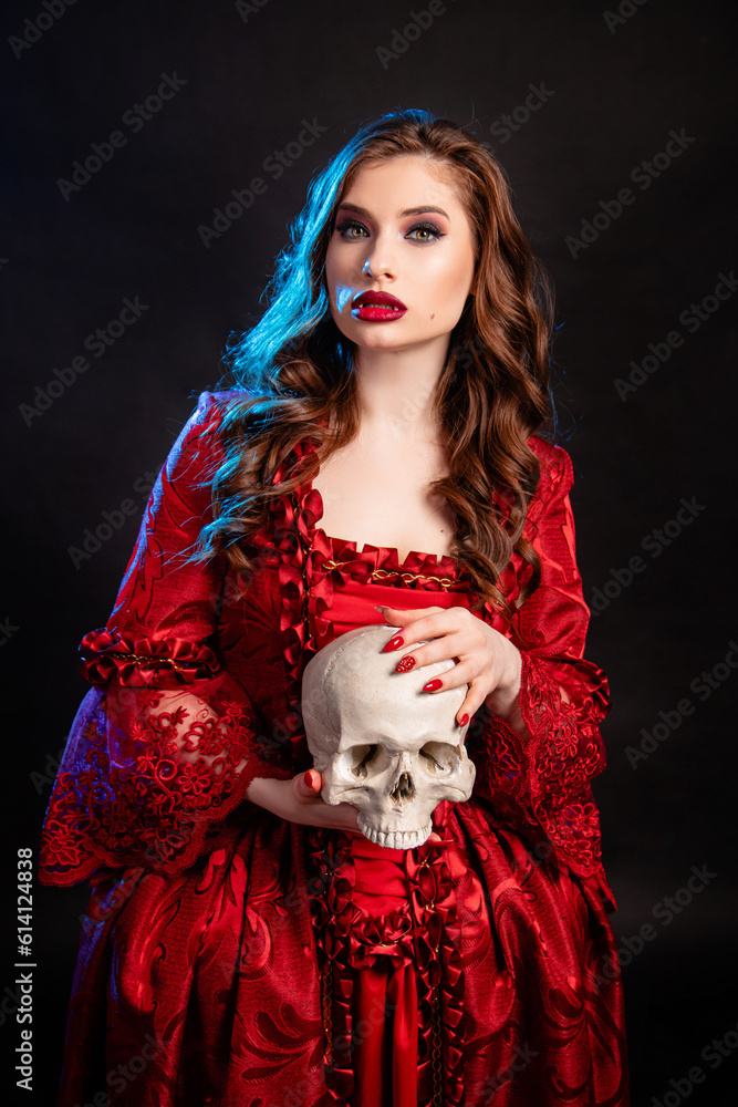 Portrait of a young, attractive vampire woman in a red dress in the ...
