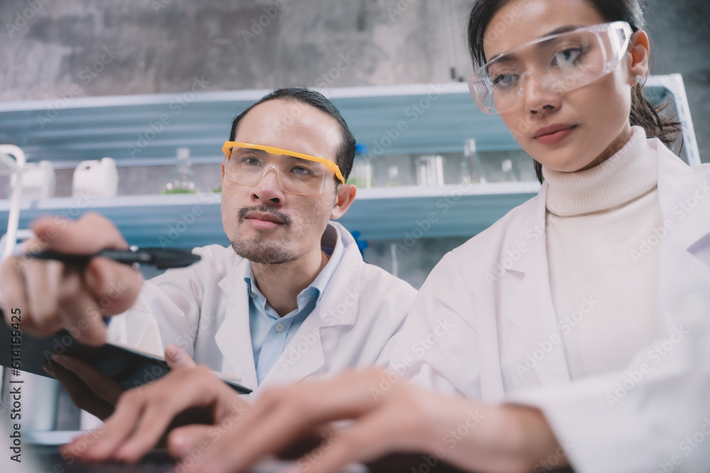 Two research people are comparing information one is working behind a ...