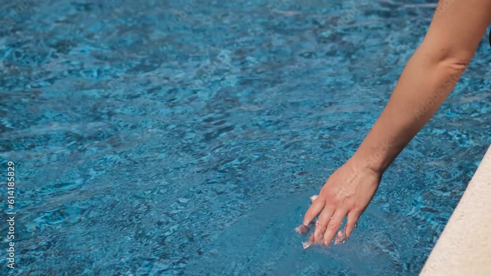 Young beautiful woman is moving a hand through water surface. Happy ...