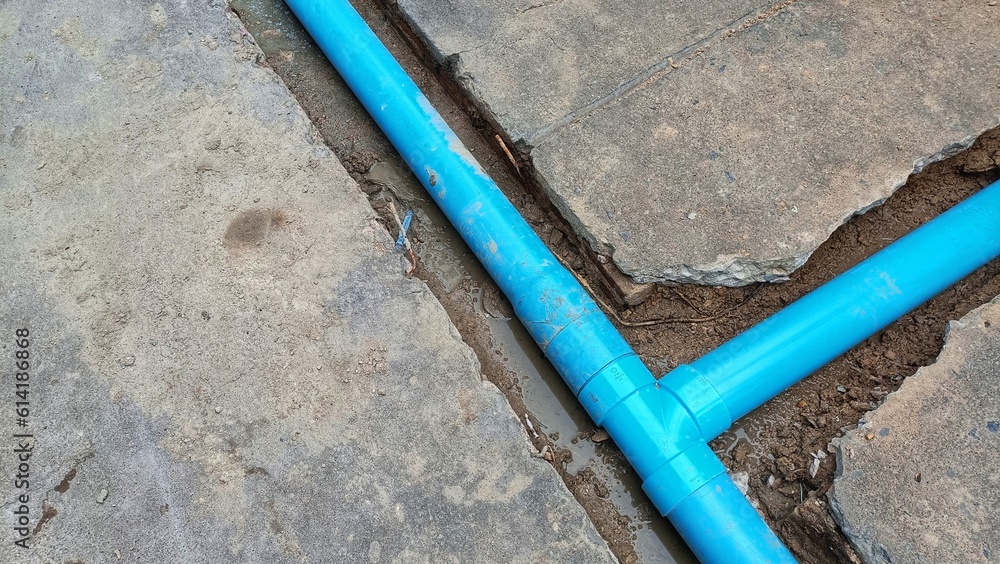 Plumbing pipes are buried underground with blue PVC pipes. On the ...
