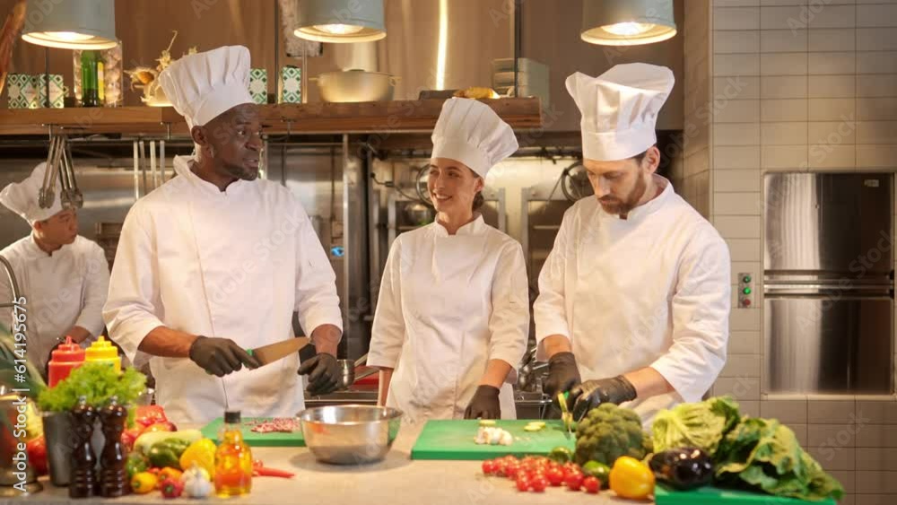 Teamwork of multicultural chefs cooking vegitables dishes in restaurant ...