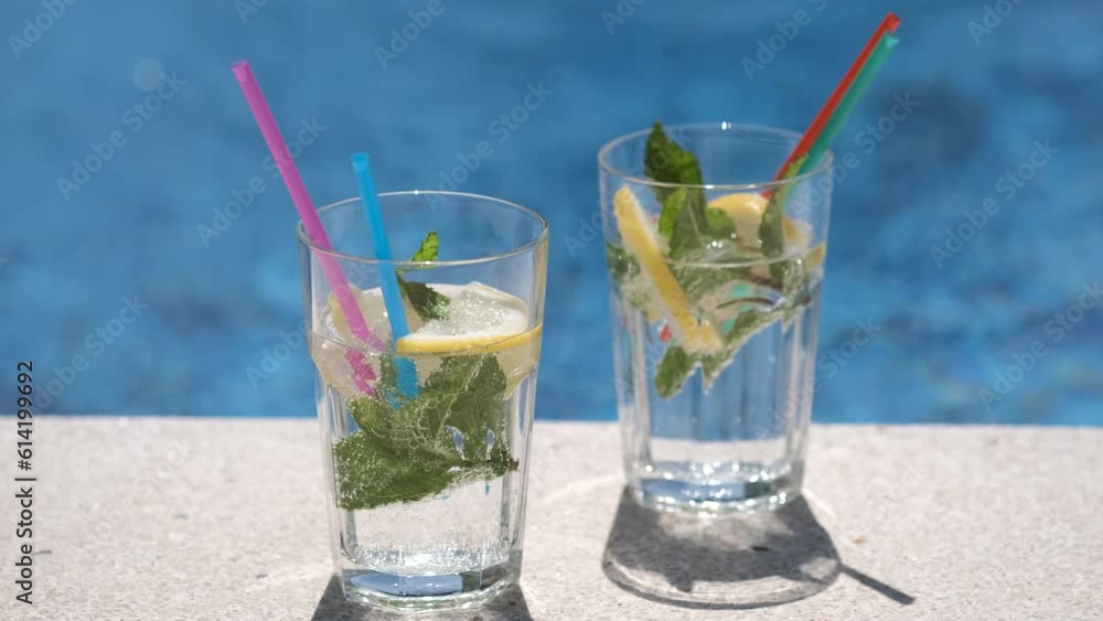 Close up of fresh lemon infused mineral water with gas or soda drinks in glasses with mint ...