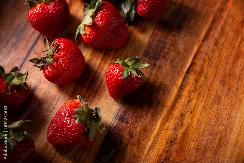 Fresh organic strawberries (fragaria) on wooden table. Also known as ...
