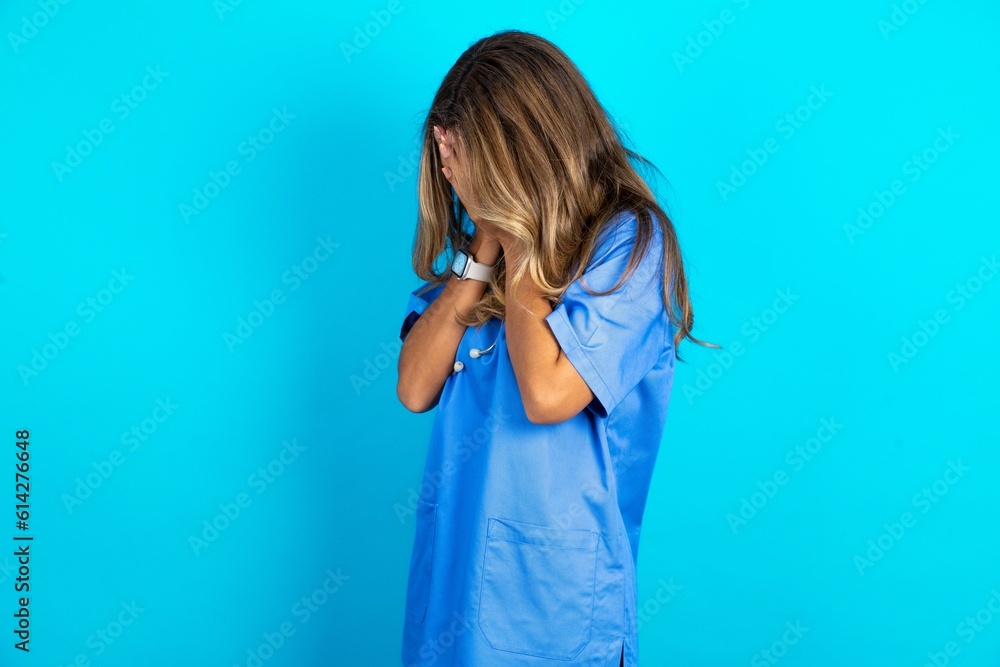 Sad Young beautiful doctor woman standing over blue studio background ...