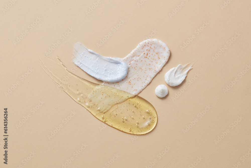 Different cosmetic textures of face cream, serum and lotion on beige ...