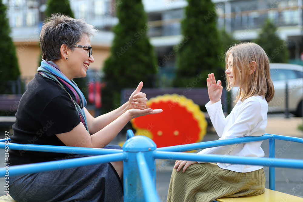 Smiling mature woman talking sign language with a child on the ...