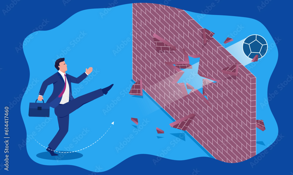 Break down barriers. A business man kicks a ball through a wall ...