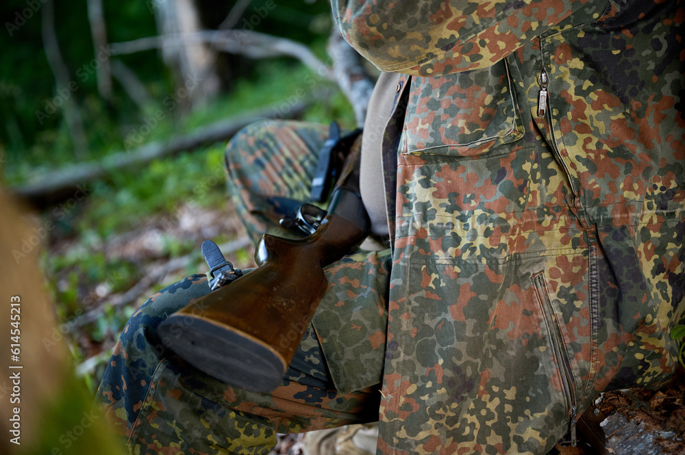 Crop view of the hunter sitting on the log in the forest. Hunter man in ...