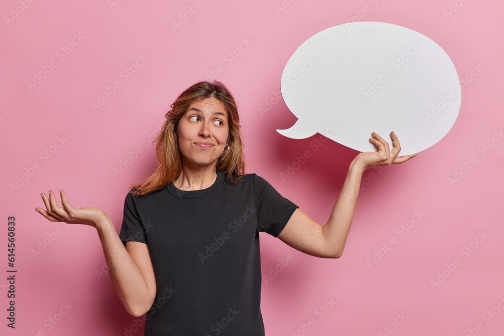 Clueless hesitant European woman holds empty speech bubble in her hand ...
