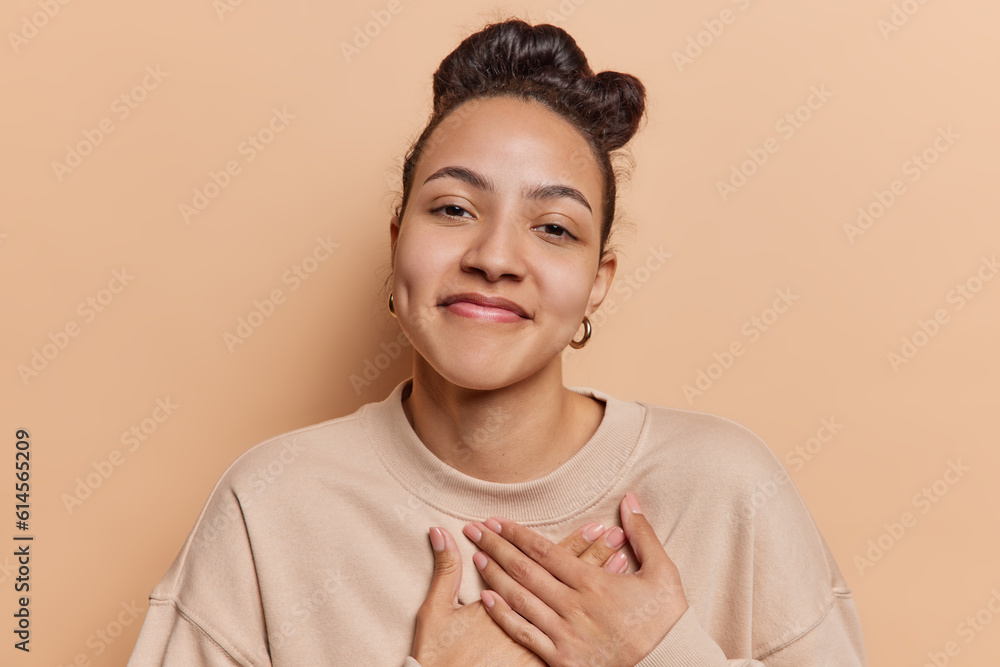 Photo of pleased Latin woman tenderly places her hands on heart ...