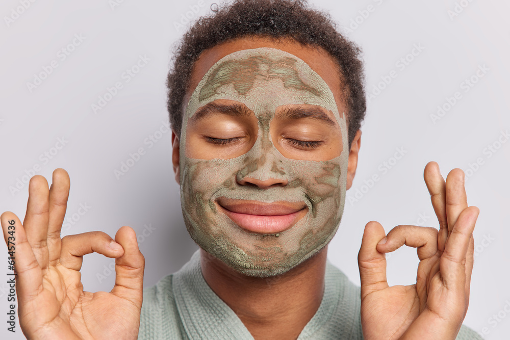 Horizontal shot of young man closes his eyes and spreads hands wide in ...