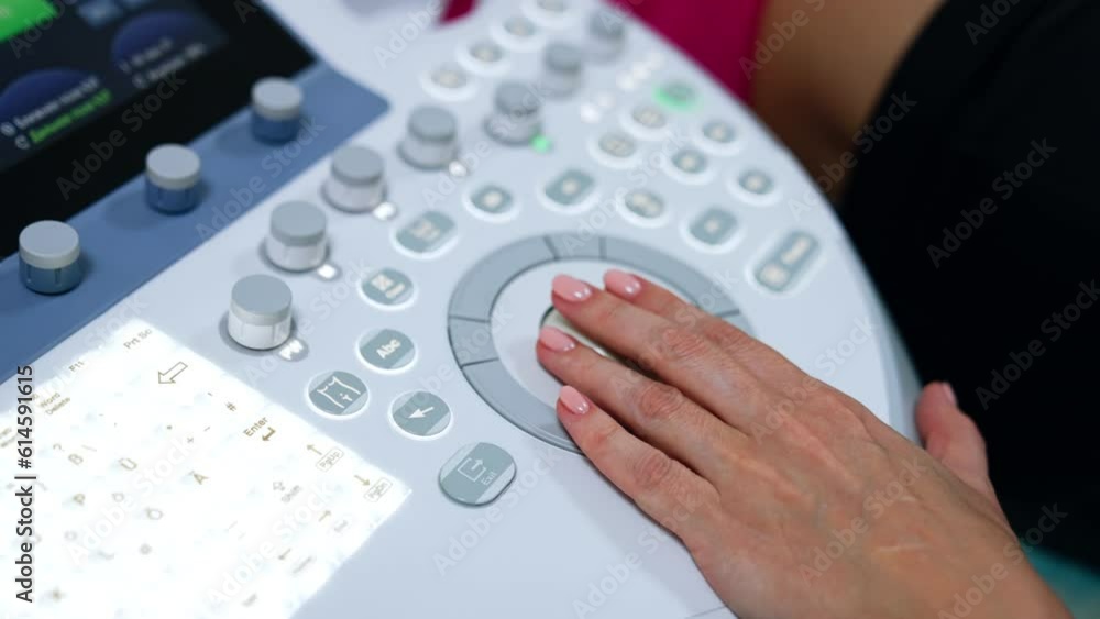 Female medic's hand on the keyboard of ultrasound machine. Doctor is ...