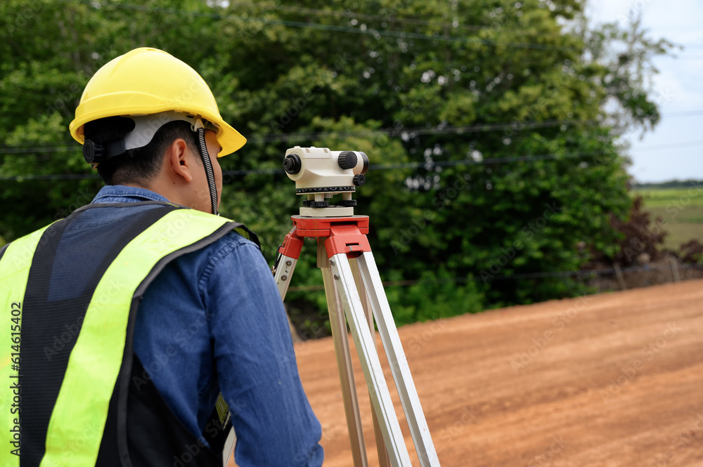 Asian surveyor engineer checking level of soil with Surveyor's ...