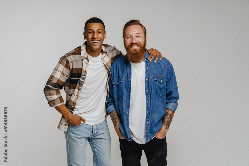 Foto de Two multinational male friends smiling and posing at camera do ...