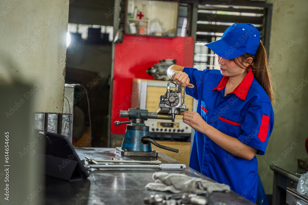 A female diesel engine mechanic in a blue uniform is working at the ...