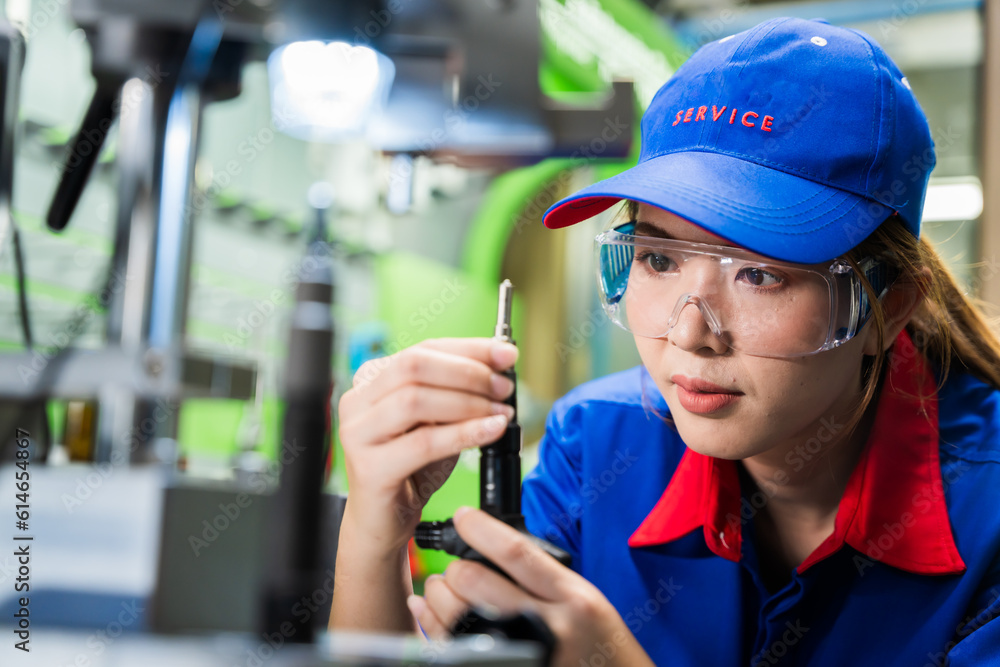 A female diesel engine mechanic in a blue uniform is working at the ...