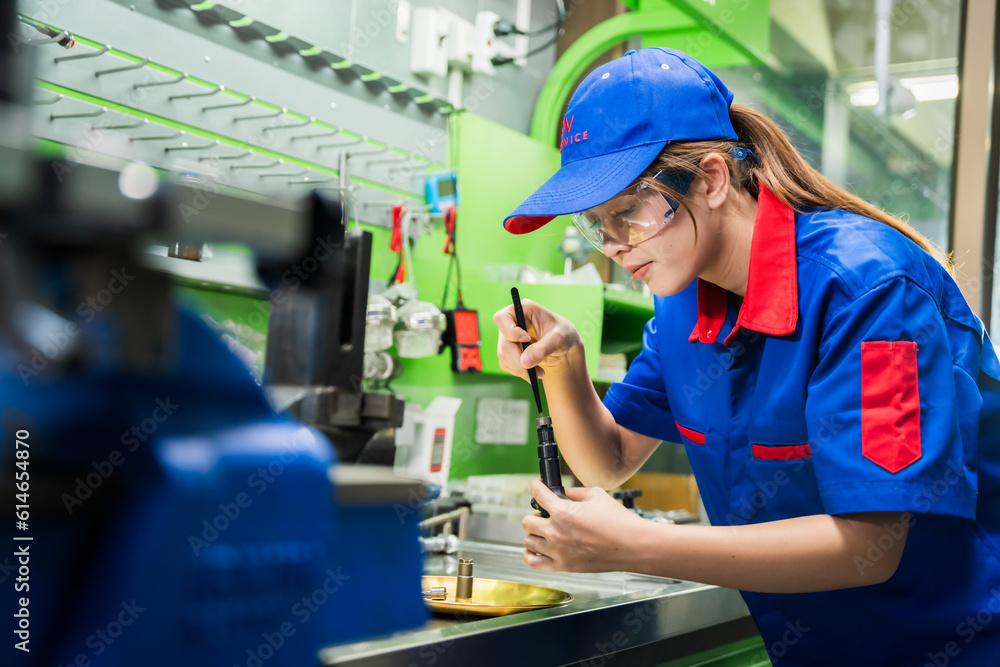 A female diesel engine mechanic in a blue uniform is working at the ...