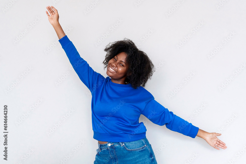 Smiling Afro woman with arms outstretched standing against white ...