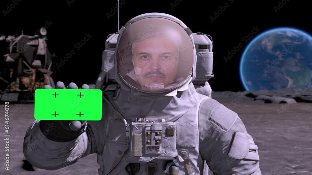 Portrait of man astronaut on Moon wearing helmet shows a smartphone ...