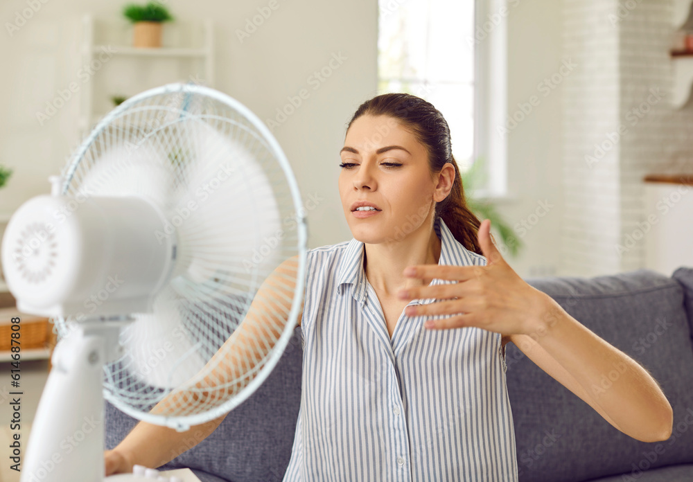 Woman suffering from summer heat and using electric fan to refresh in ...