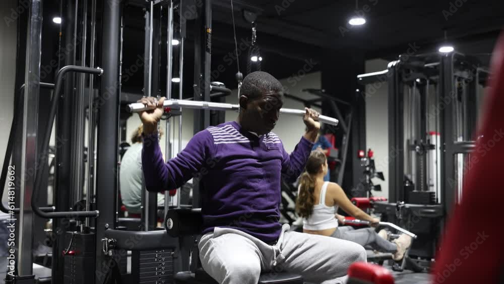 African-american man training on lat pull down machine in gym African ...