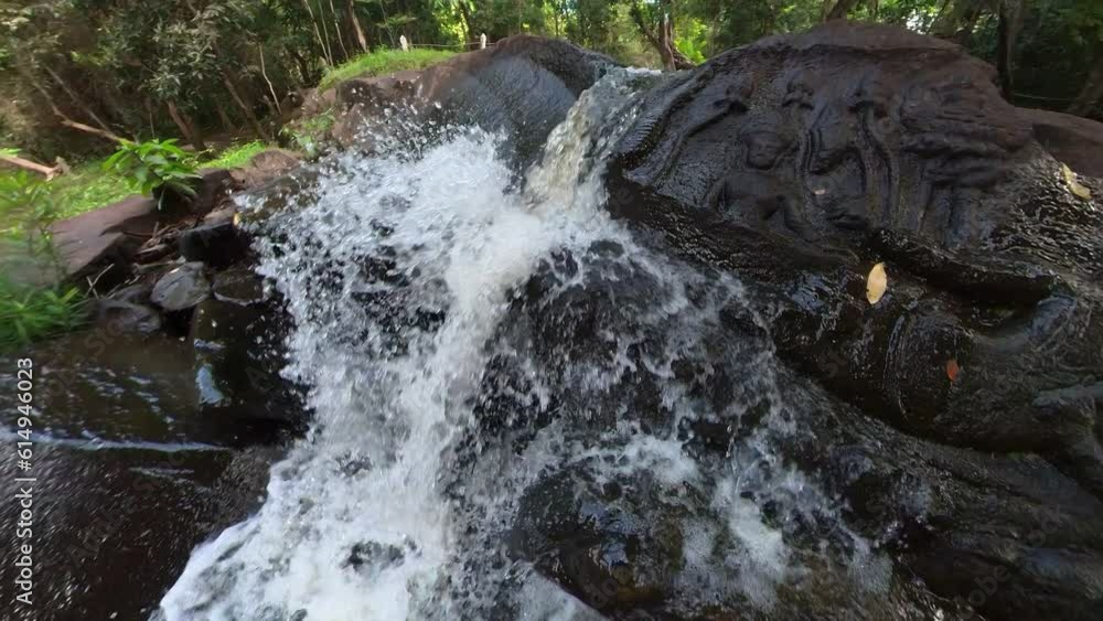 Flowing splashing waterfall over ancient Hindu rock carvings of shiva ...