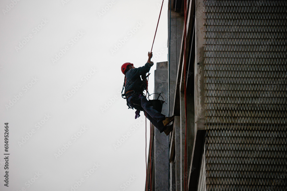 Window cleaning worker hanging on a building wearing safety equipement ...