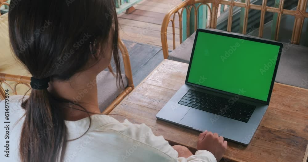 Over the shoulder shot woman student using laptop computer at cafe ...