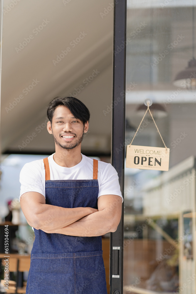 Black male shopkeeper wearing apron with open sign A waitress stands at ...