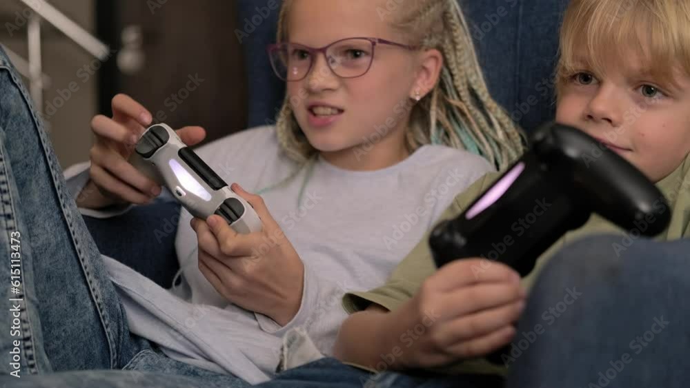 boy and girl playing video game console using joystick or controller ...