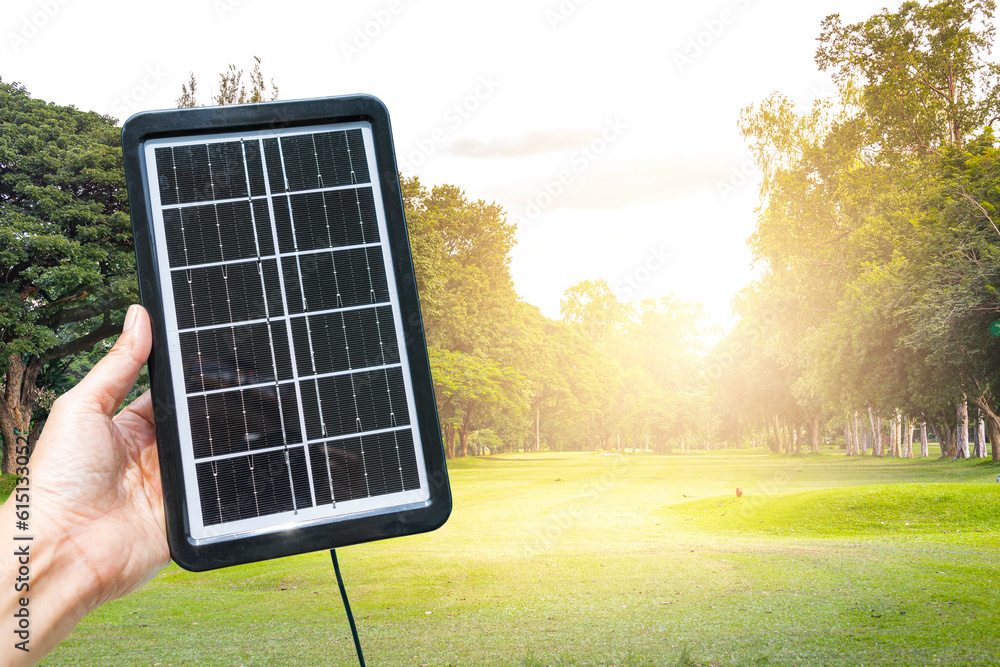 Portable solar cell panel in girl hand over nature background with ...