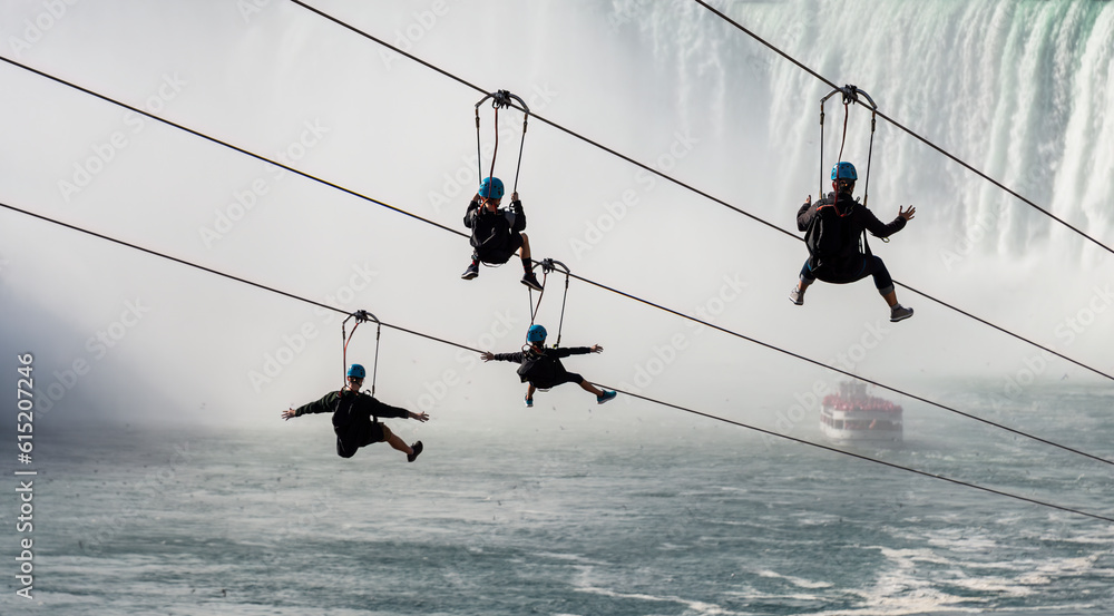 Kids riding the Zipline over Niagara Falls. Tourist boat cruising on ...