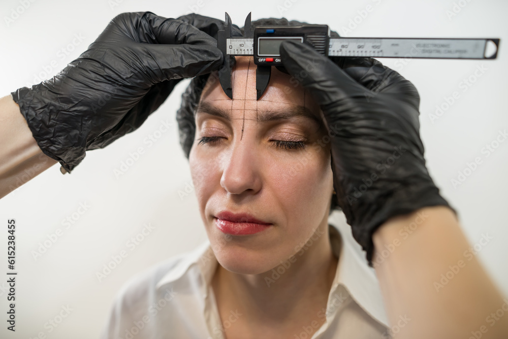Eyebrow reshaping. Stylist measuring eyebrows with a ruler. Stock Photo ...