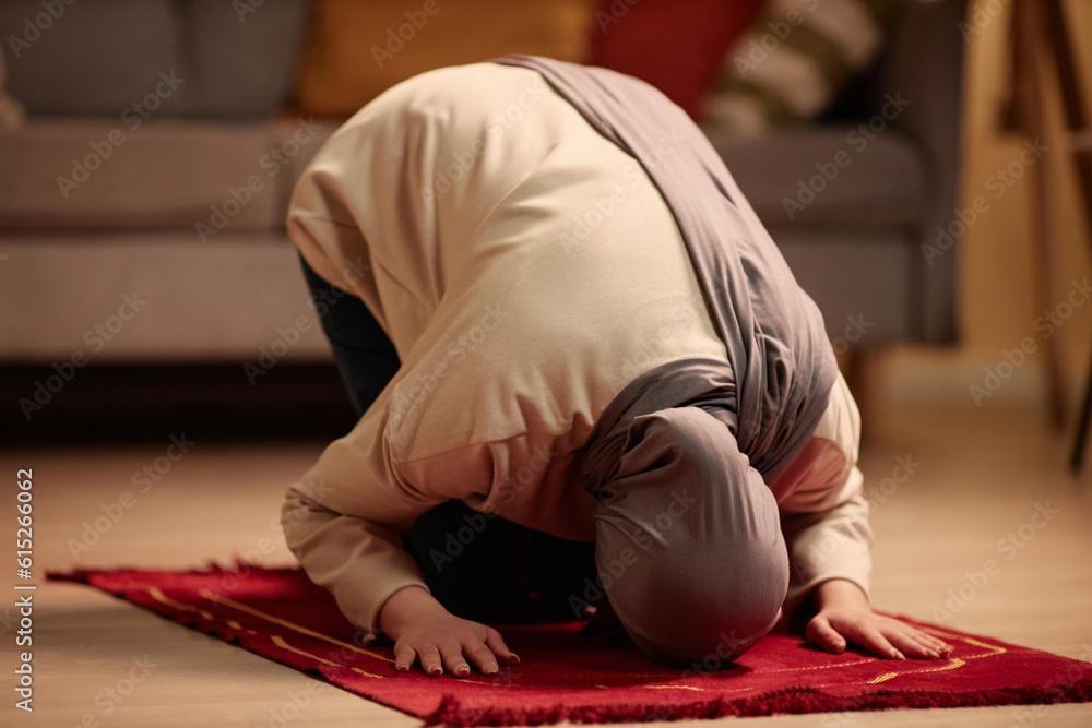 Back of young Muslim woman in hijab and beige pullover bending forwards ...