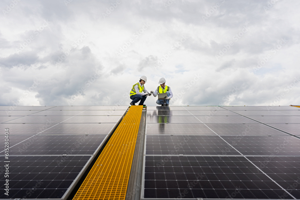 Two young Asian engineers checking the installation of solar panels on ...
