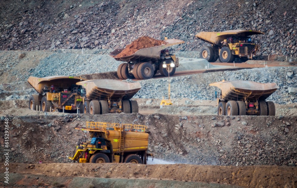 Six trucks in a busy modern gold mine in Western Australia. One water ...