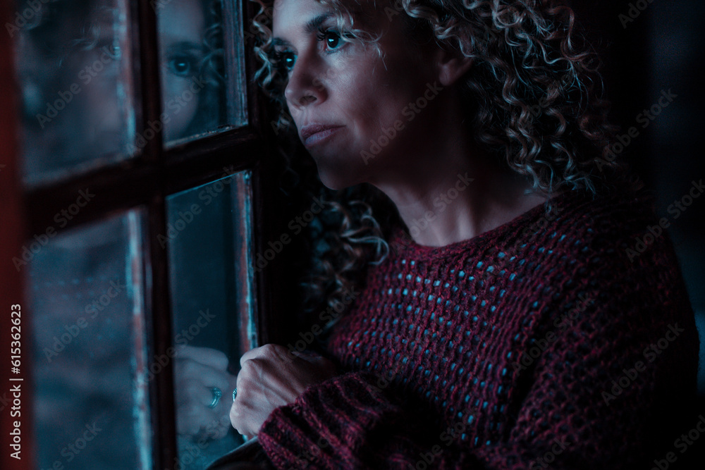 Serious and sad woman looking outside the window at home indoor ...