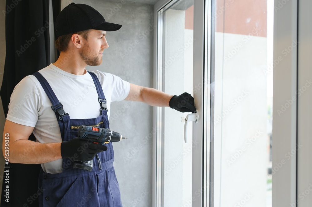 handsome young man installing bay window in new house construction site ...