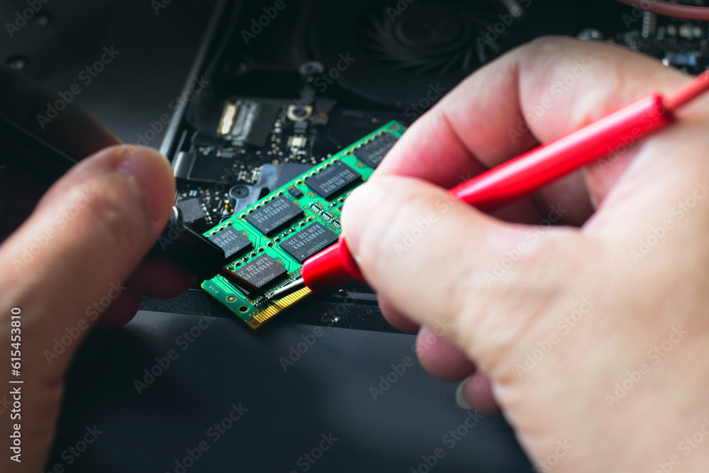 computer technician A laptop motherboard repair technician is using an ...