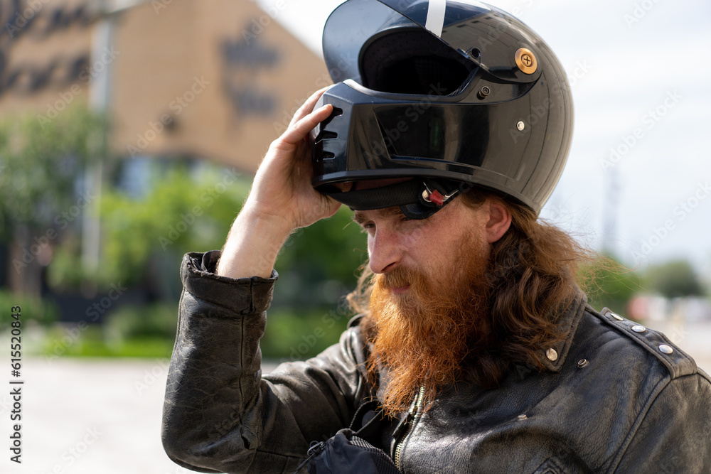 brutal red bearded biker sitting on a black motorcycle after a race ...