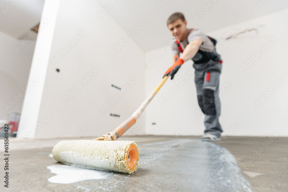 Closeup floor priming process. Worker use primer on concrete floor ...