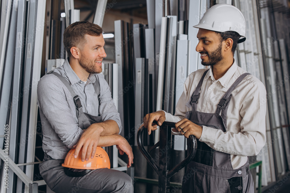 Portrait of two international workers wearing hardhats taking break ...