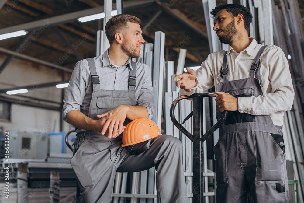 Portrait of two international workers wearing hardhats taking break ...