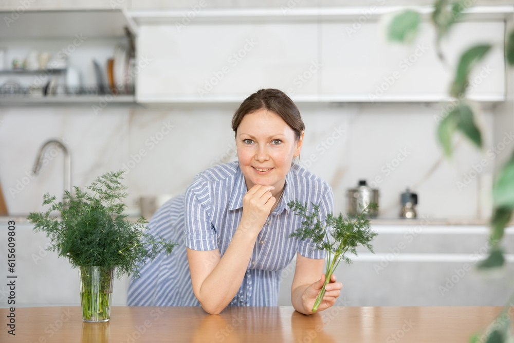 Young housewife took bunch of greens for cooking lunch. Woman in blue ...