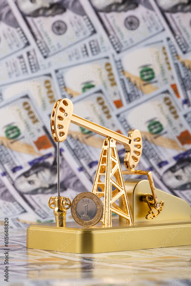 A coin of 1 riyal of the Kingdom of Saudi Arabia and a golden oil pump ...