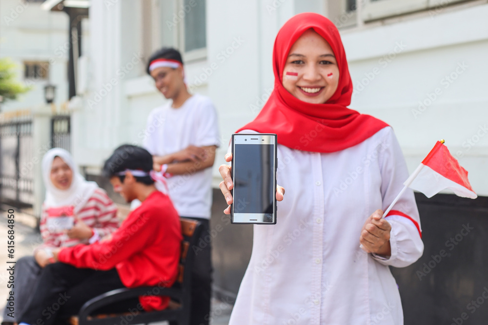 Young Asian woman showing mobile phone screen while holding Indonesian ...