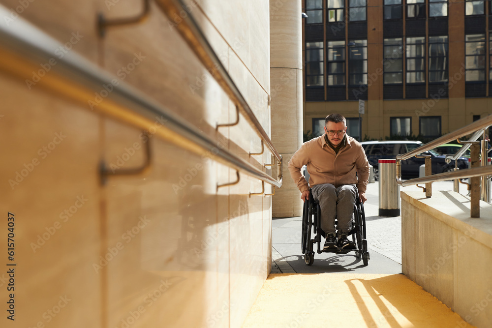 Young man with disability using ramp to move up the building Stock ...